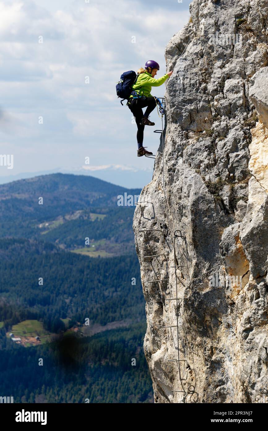 A person climbing a via ferrata route on a vertical rock wall. Sports ...