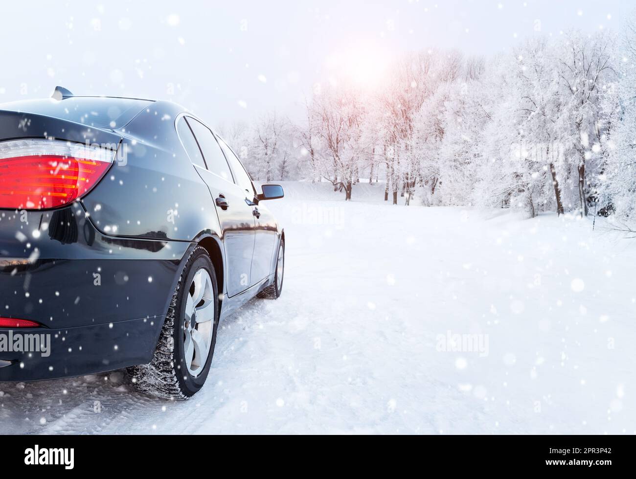 Black car on a winter road in a snowy forest, winter journey. Modern ...