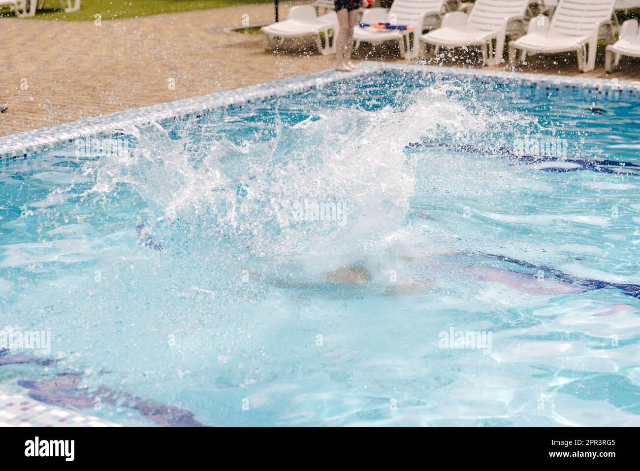 Water splashes after man jumping and diving into the swimming pool ...