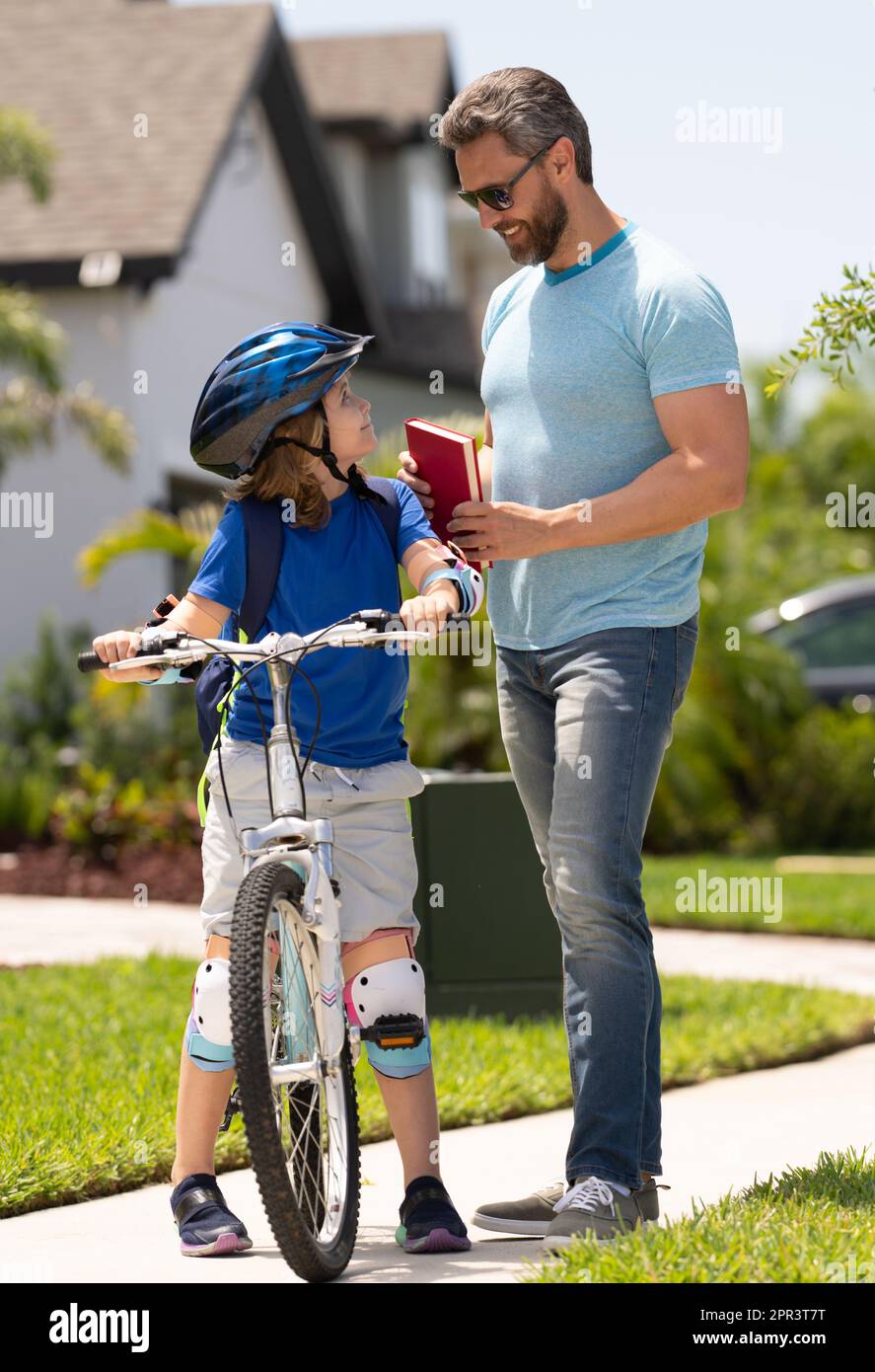 Father helping son get ready for school. Father teaching son cycling ...