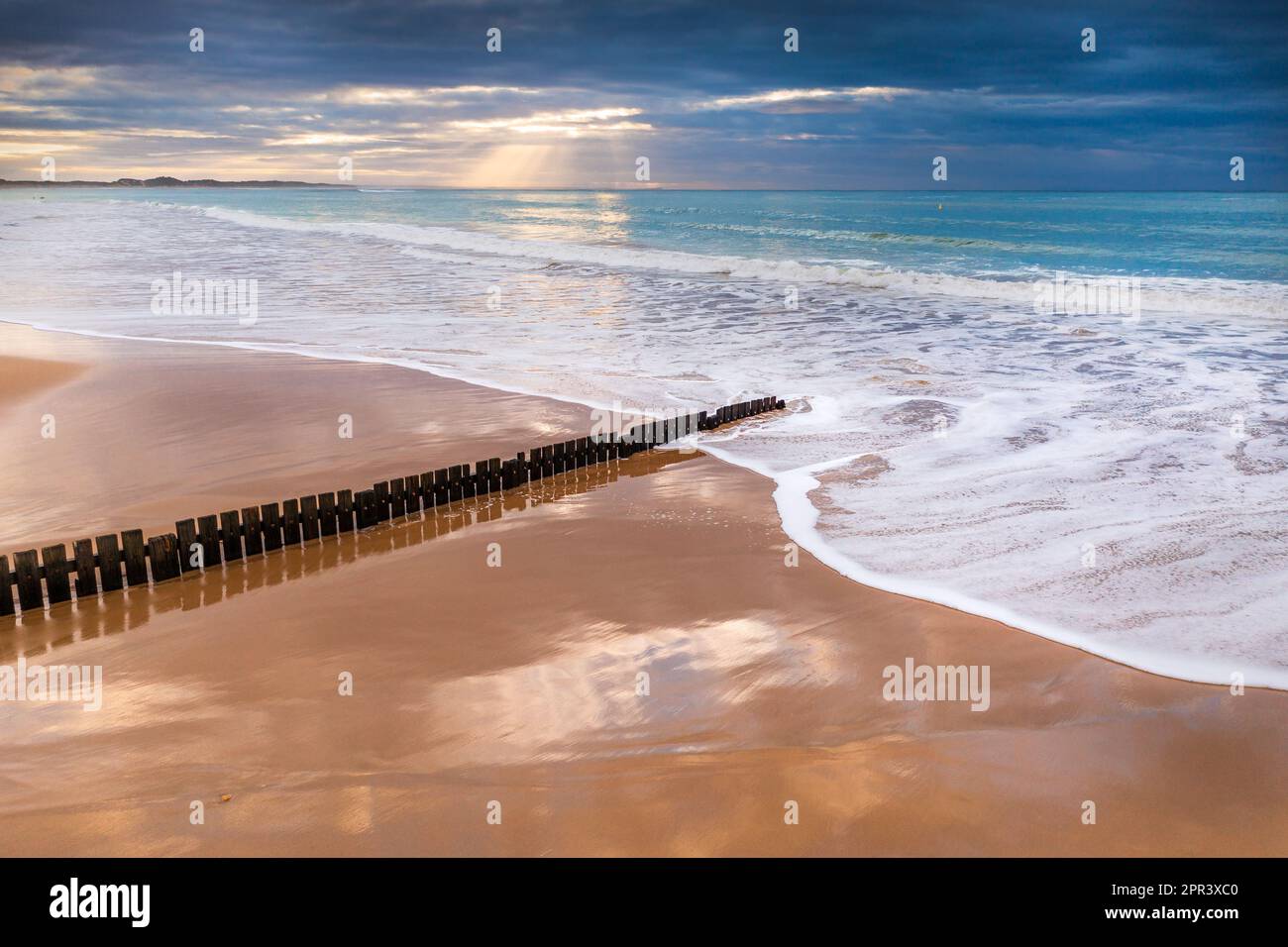 Aerial view of a sunrise over a sandy beach with white waves around a ...