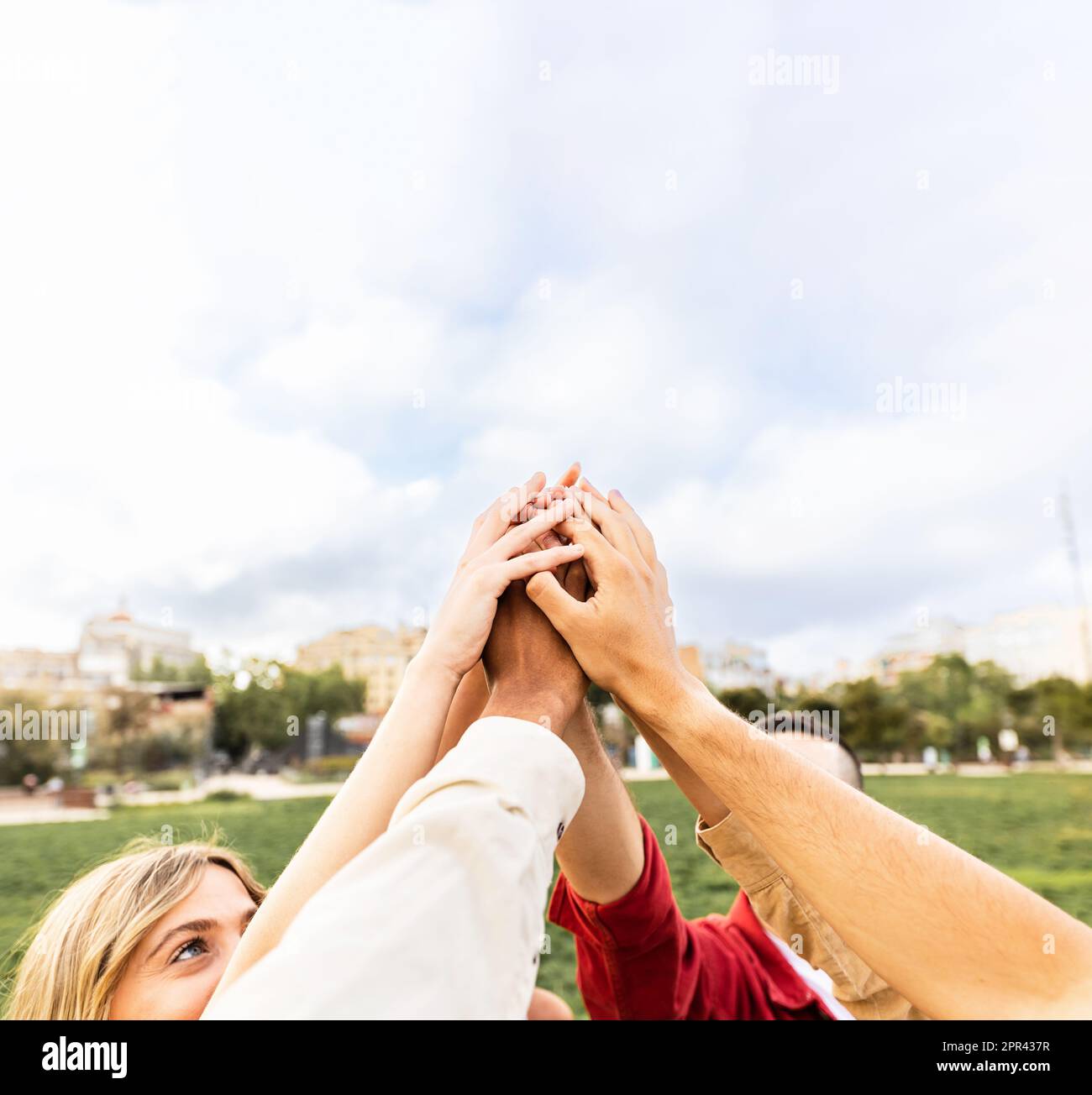 Diverse young adult people stacking hands showing unity outdoors Stock ...