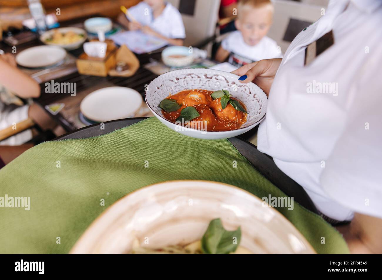 First person view of waitress bring dish to customer. Restaurant ...