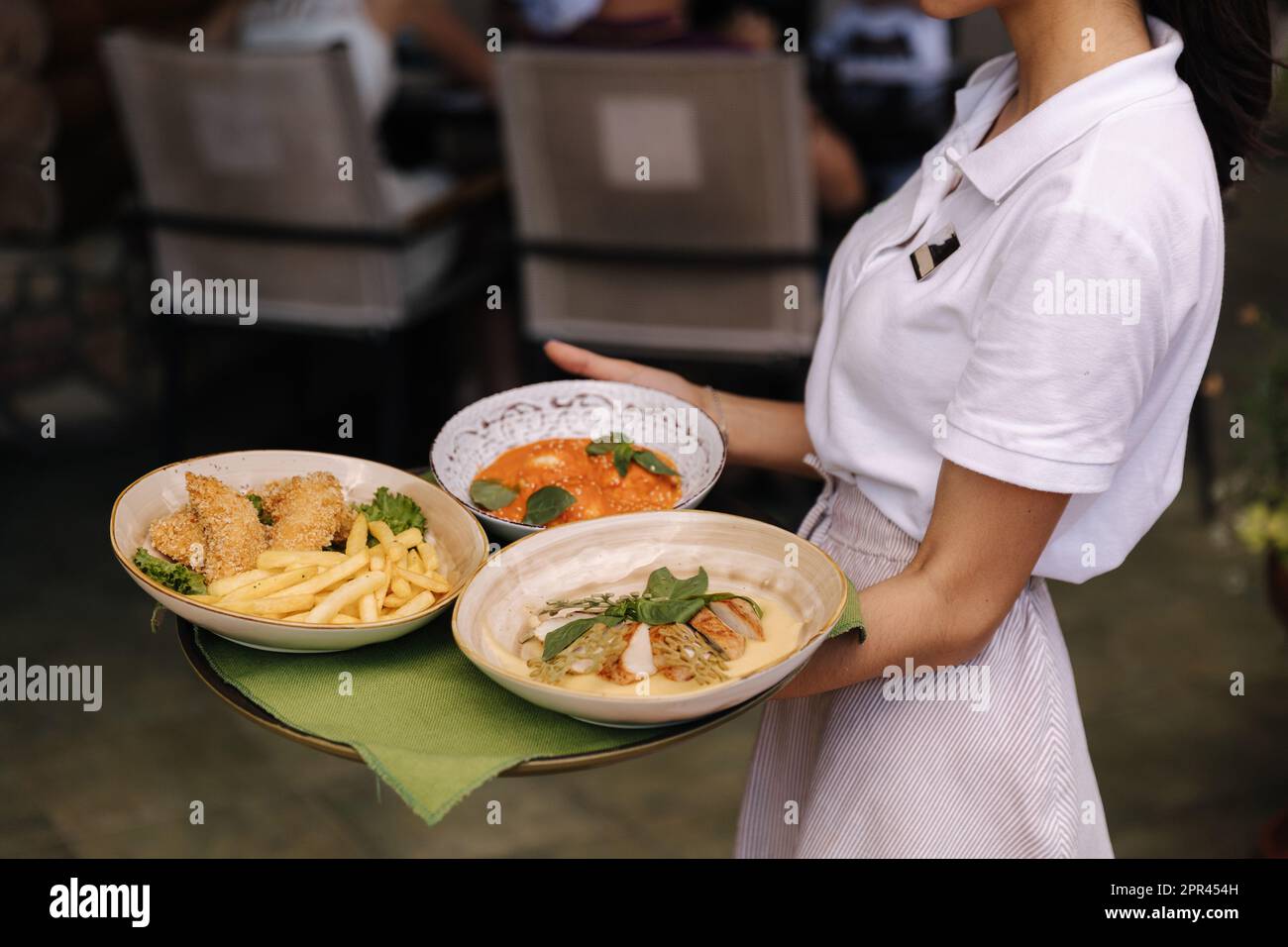 Side view of female waitress told tree dishes on tray. Middle selection ...