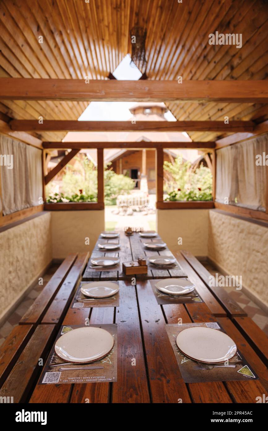 Wooden gazebo with table setting inside. Rustic restaurant in village ...