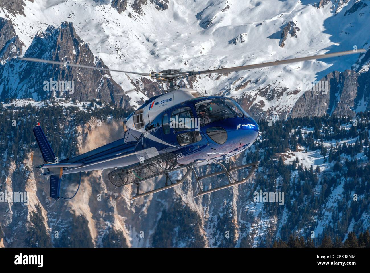 Eurocopter AS-350B3 helicopter landing, against a snow covered alpine ...