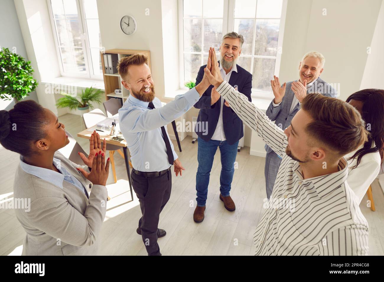 Happy colleagues giving high five at meeting at office, celebrating ...