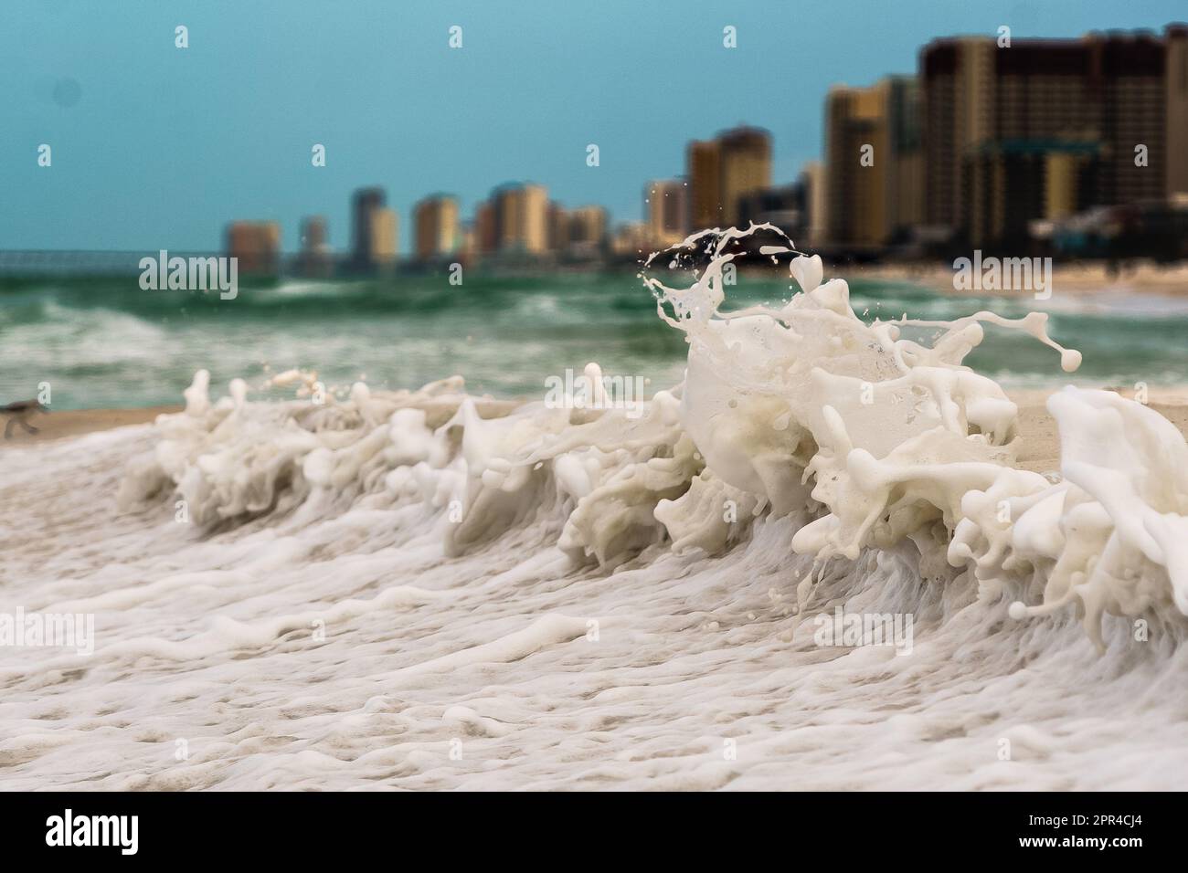 A calm ocean with white capped foamy waves rolling in from the horizon ...