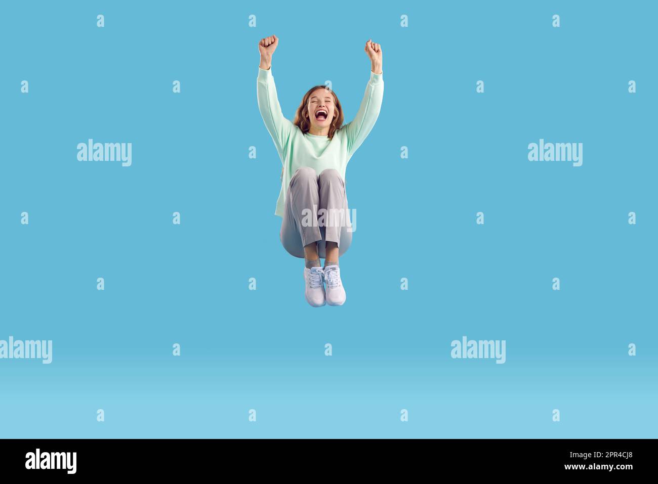 Happy excited woman screaming and jumping high in the air on blue ...