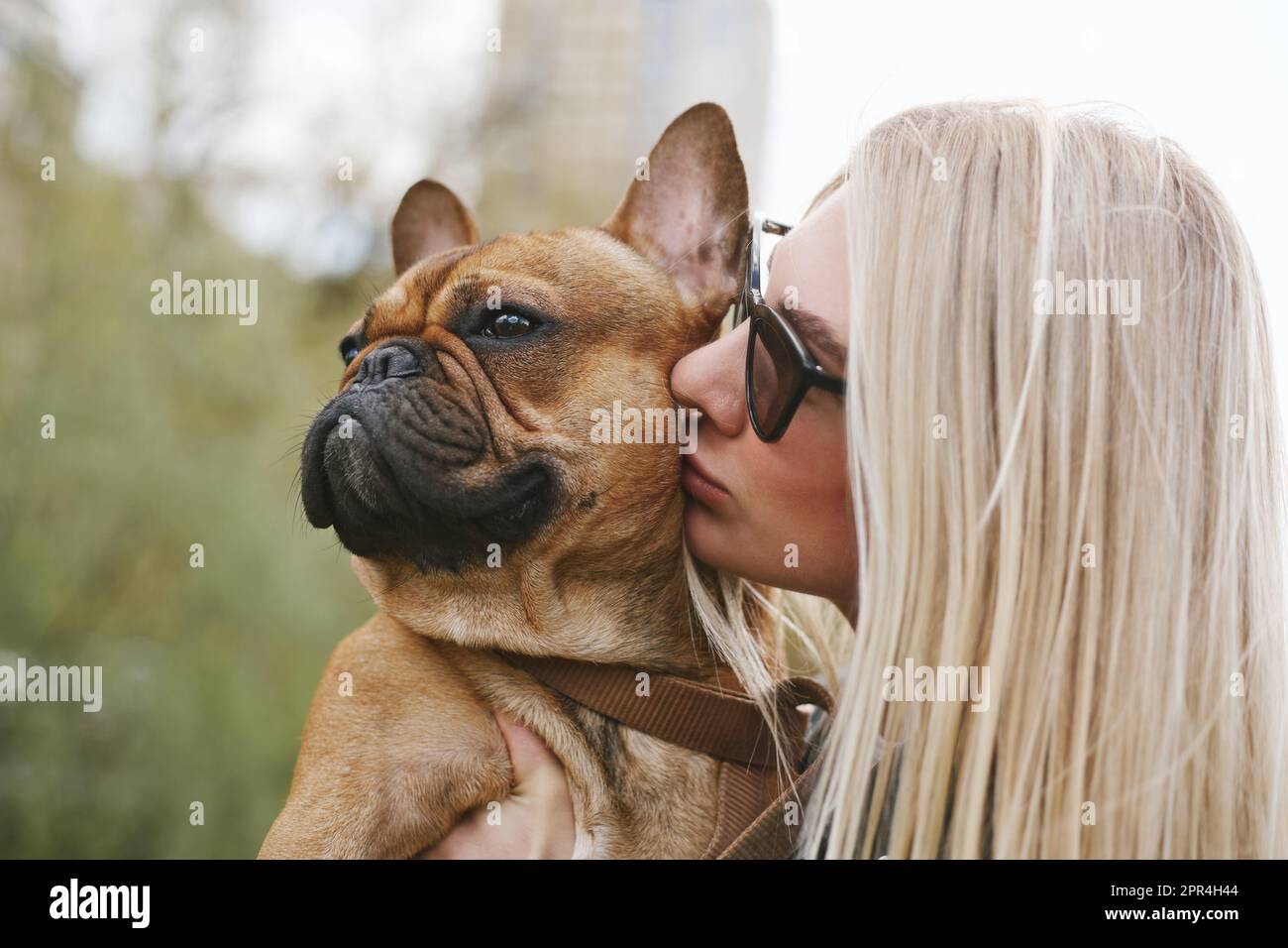 Beautiful young woman kissing her dog. Loving owner giving her pet a ...
