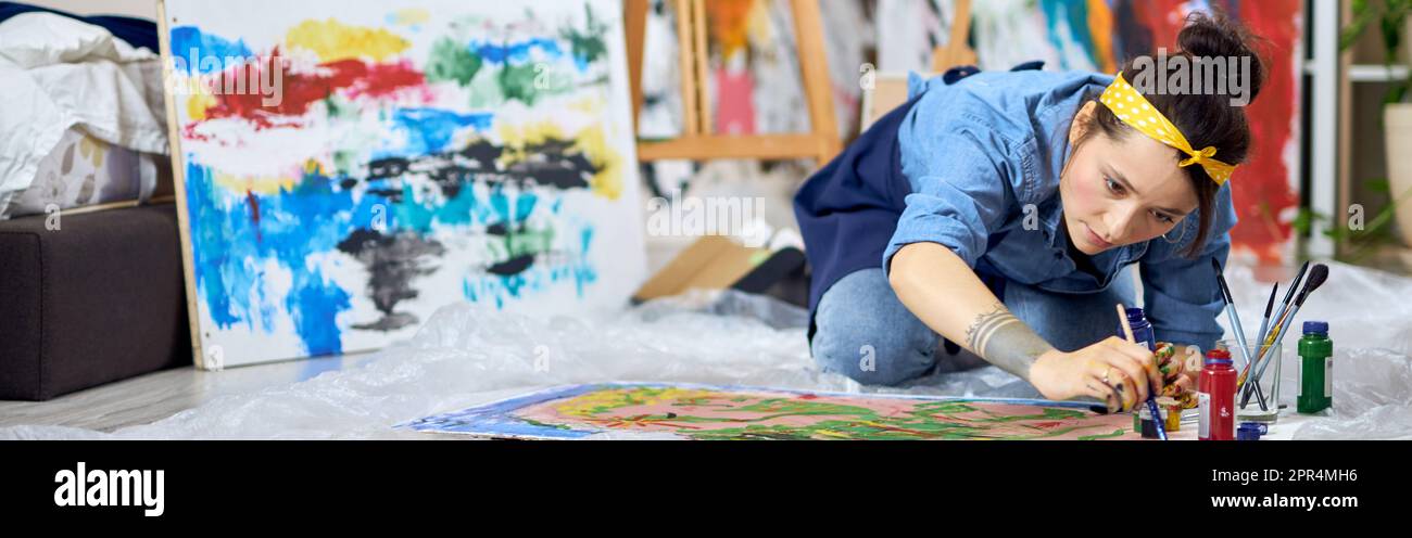 Talented female painter in apron choosing paint color, holding ...