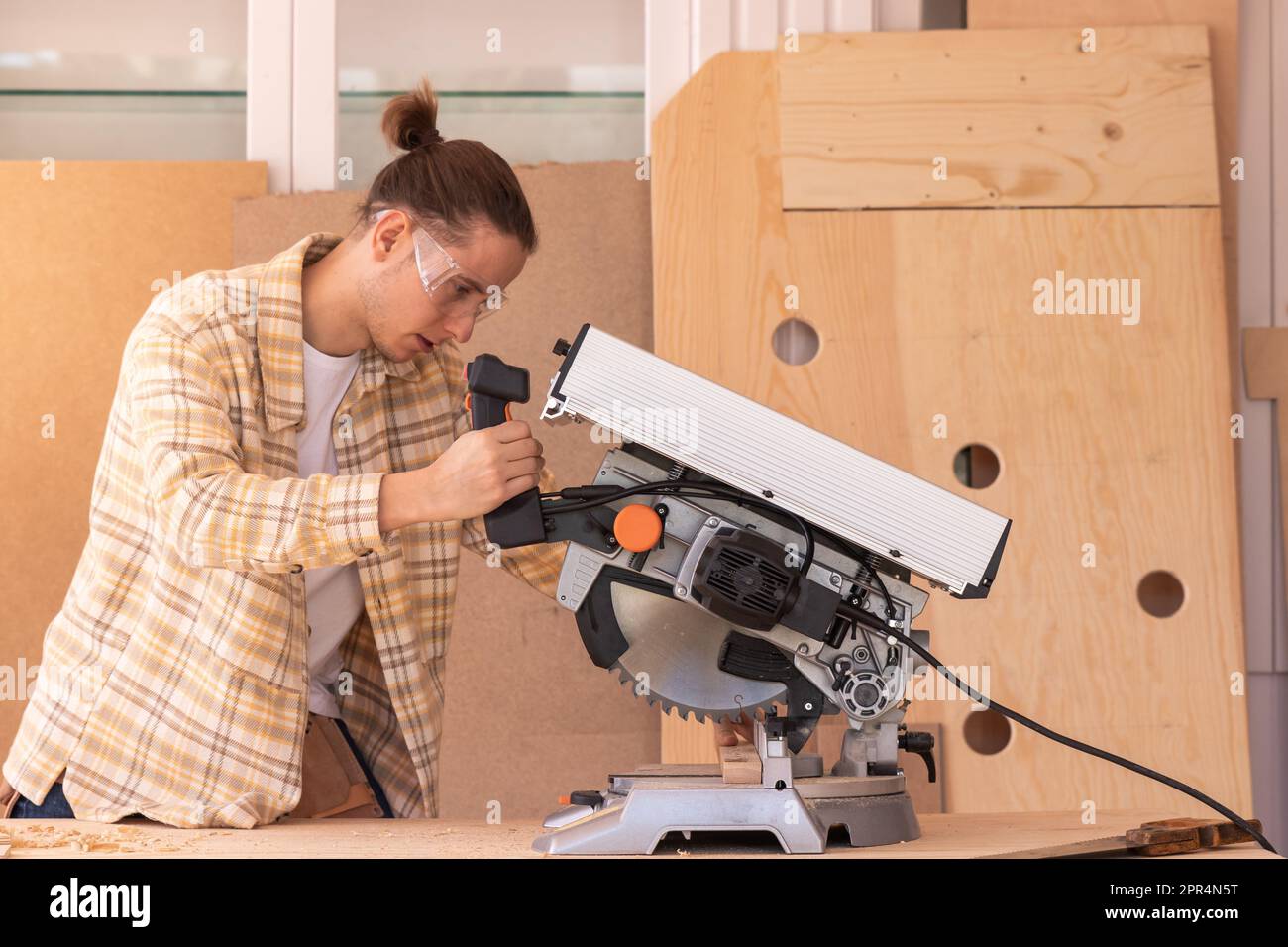 Side view of concentrated workman sawing wooden block with circular saw ...