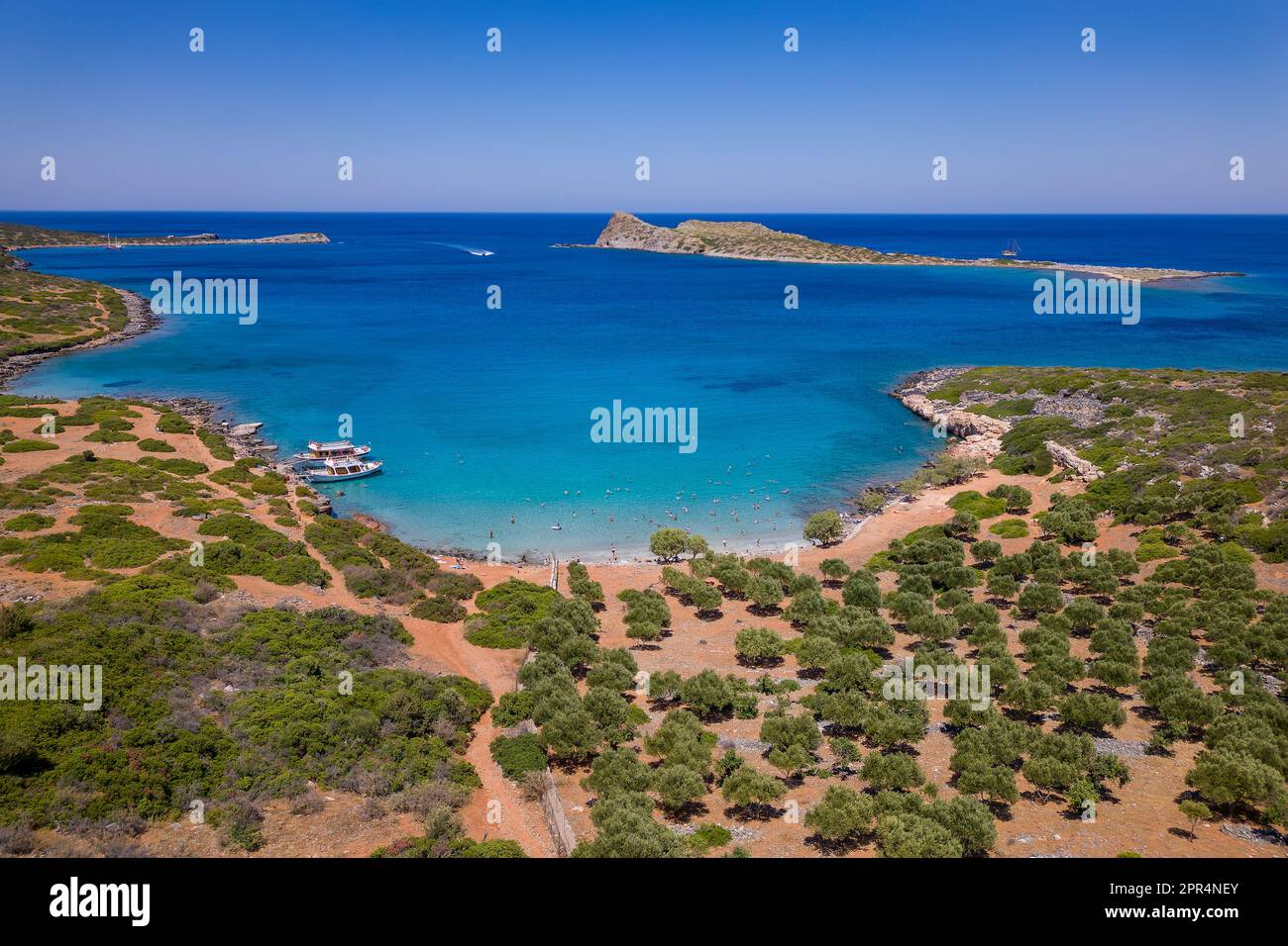 Aerial view of a small beach and crystal clear ocean with swimmers on a ...