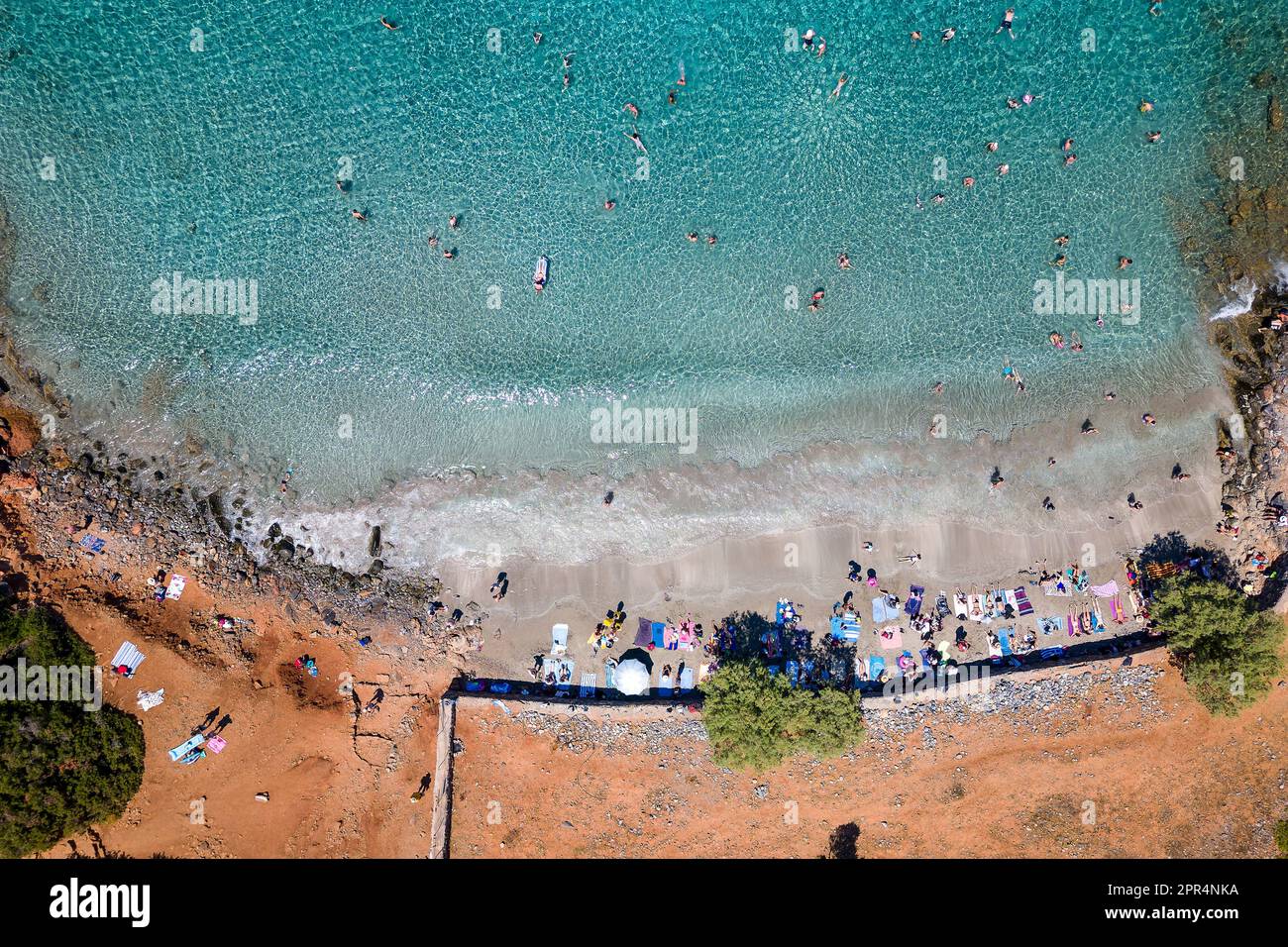 Top down aerial view of tourists on a small beach with crystal clear ...