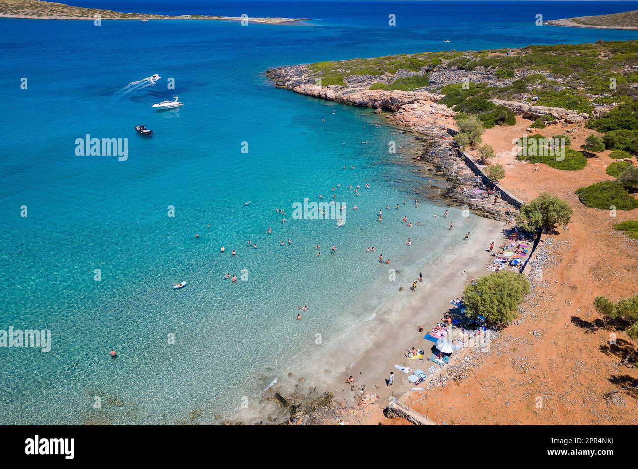 Aerial view of a small beach and crystal clear ocean with swimmers on a ...