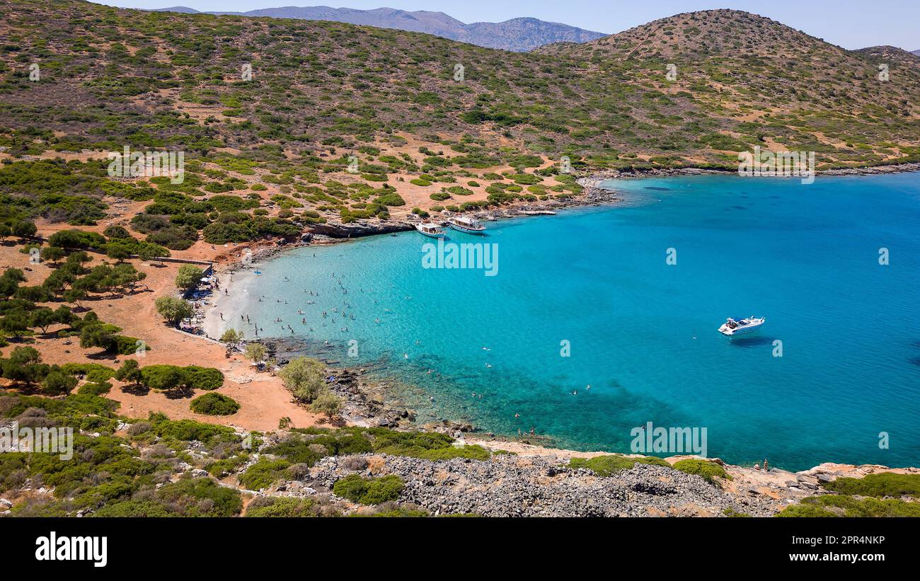 Aerial view of a small beach and crystal clear ocean with swimmers on a ...