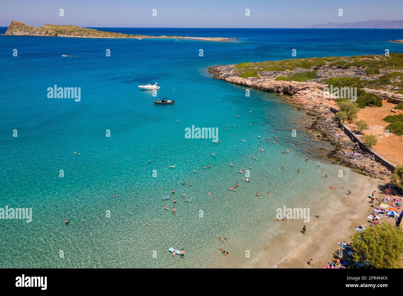 Aerial view of a small beach and crystal clear ocean with swimmers on a ...