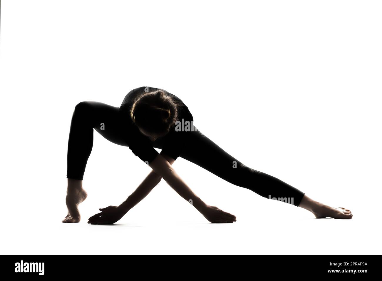 A woman in a yoga asana pose with her arms extended on a white ...