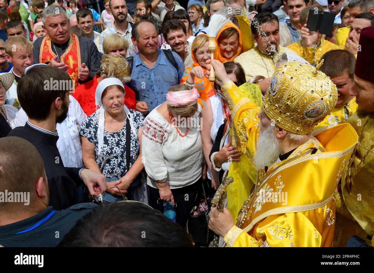 Orthodox priest blessing crowd of people with holy water. Ukrainian ...