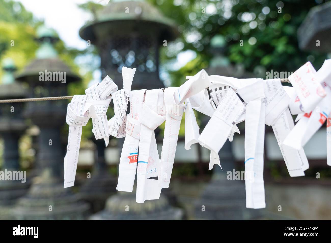 Japanese Omikuji fortune telling paper slips tied to a rope at the Ueno Tosho-gu Shrine honden ...