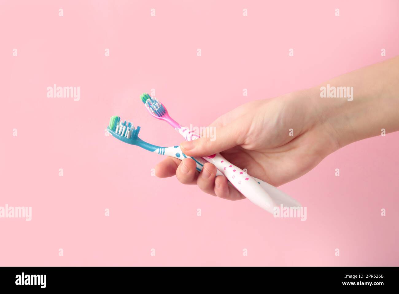 Toothbrushes in woman's hand on pink background. Top view Stock Photo ...