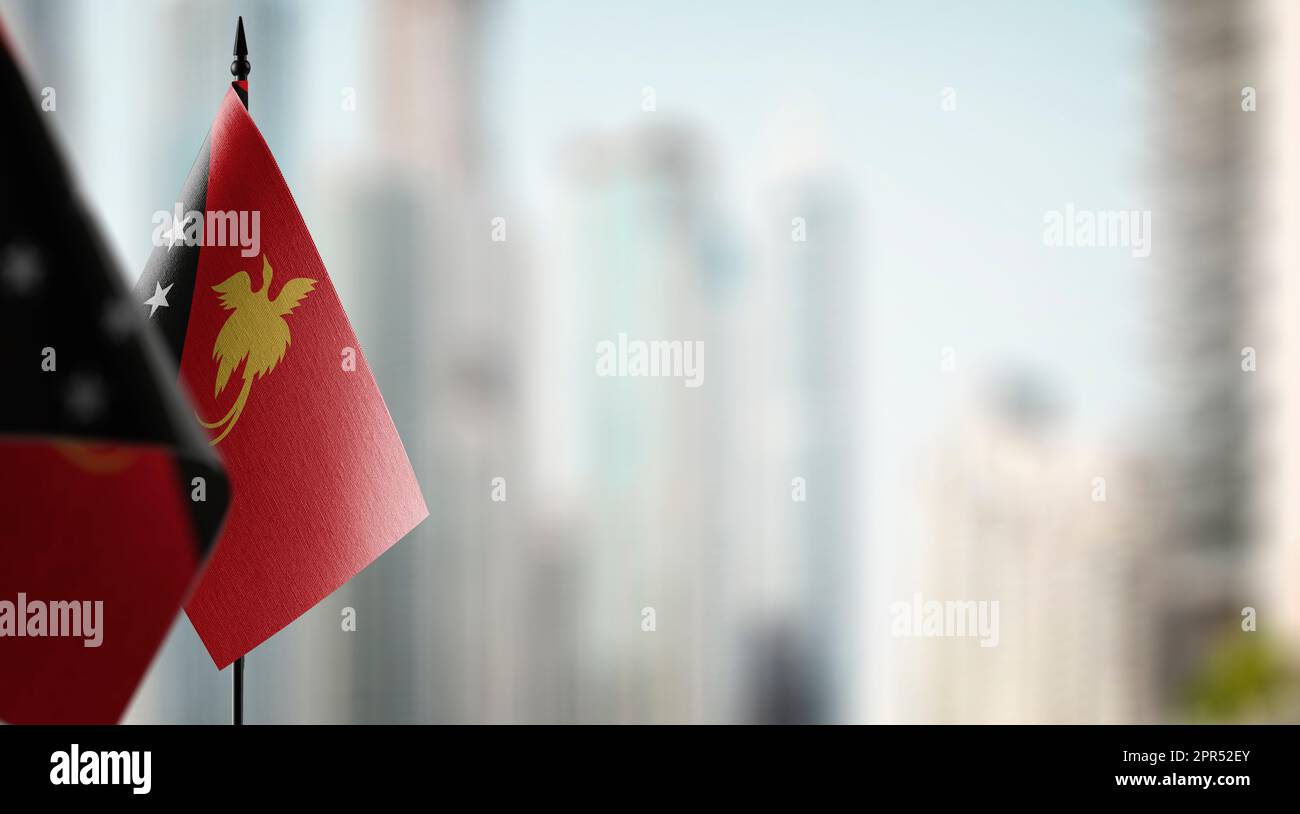 Small flags of the Papua New Guinea on an abstract blurry background ...