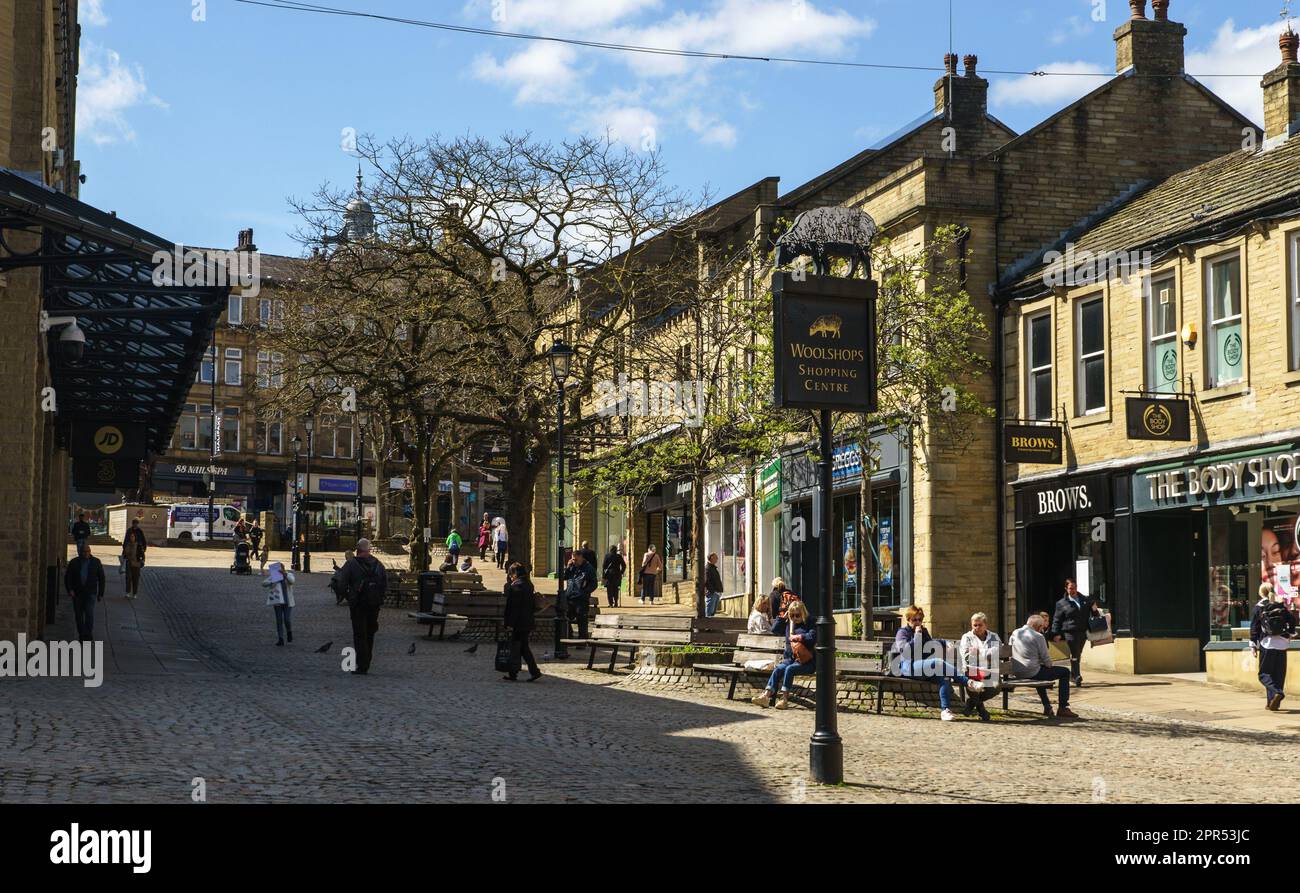 People sitting in the sunshine in the square outside the Woolshops ...