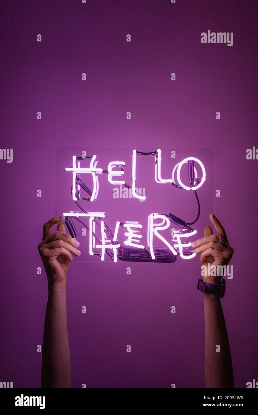 Two hands in a rainbow-colored background holding a neon sign with the ...
