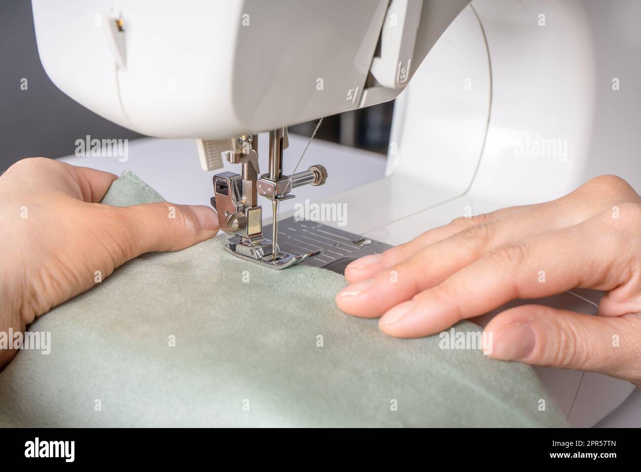 Female hands stitching white fabric on modern sewing machine at ...
