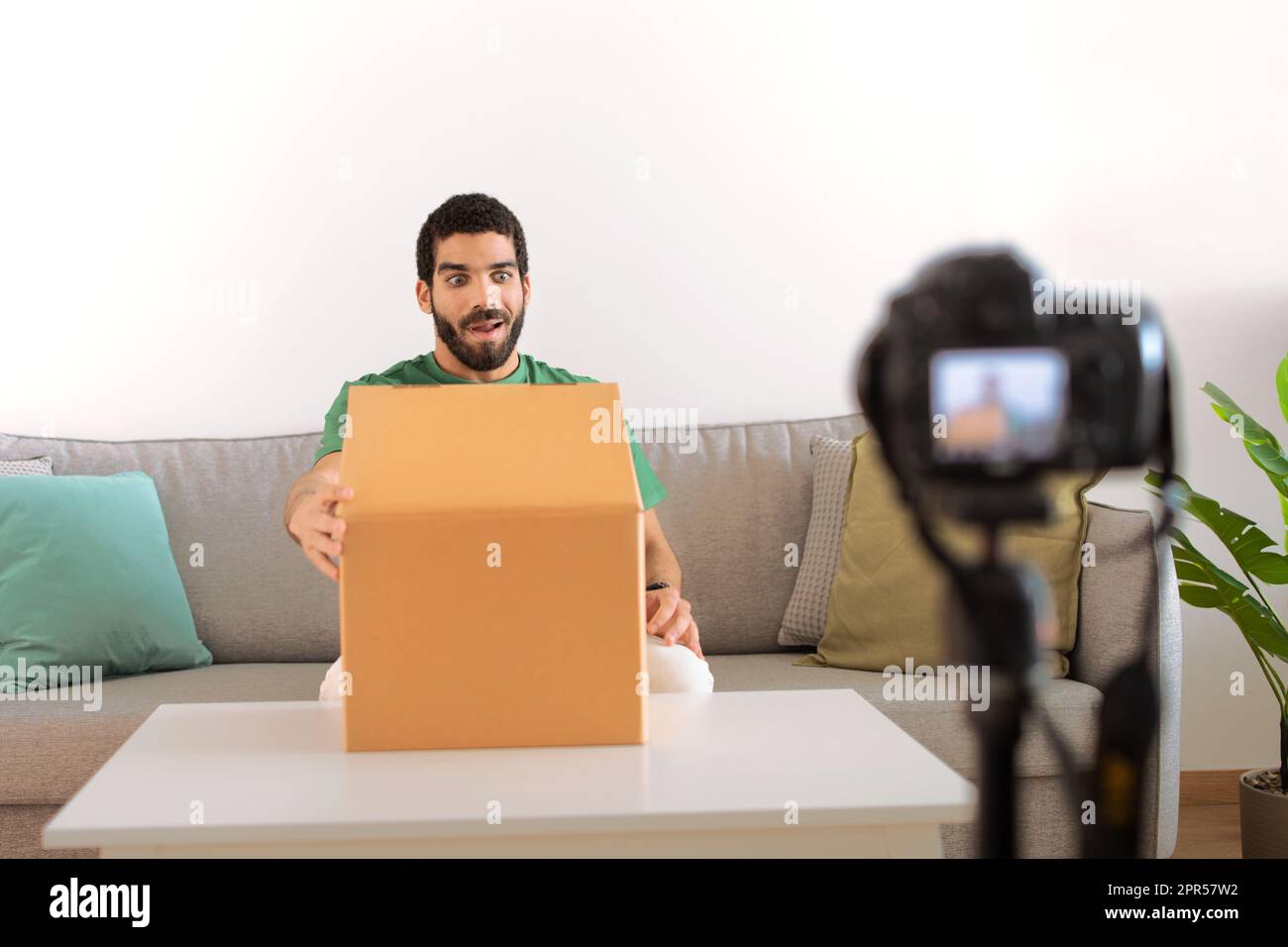 Glad surprised young middle eastern guy blogger at table unpacks ...