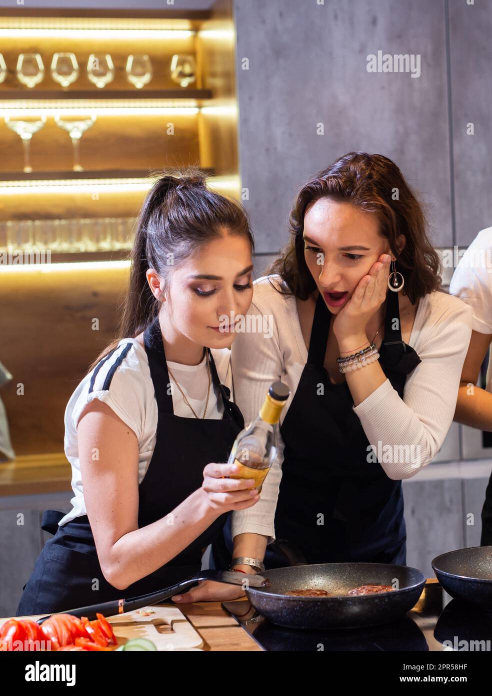 Two funny professional female chefs preparing food in large kitchen and ...