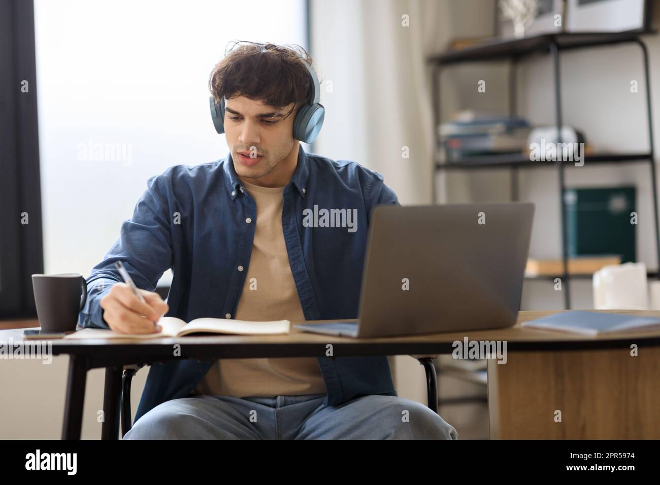 Guy Taking Notes Learning Online At Laptop Wearing Headphones Indoor ...