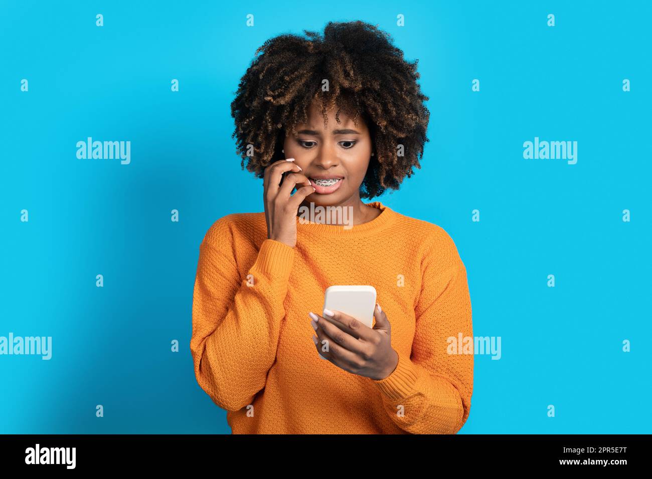 Scared young black woman looking at cell phone screen Stock Photo - Alamy