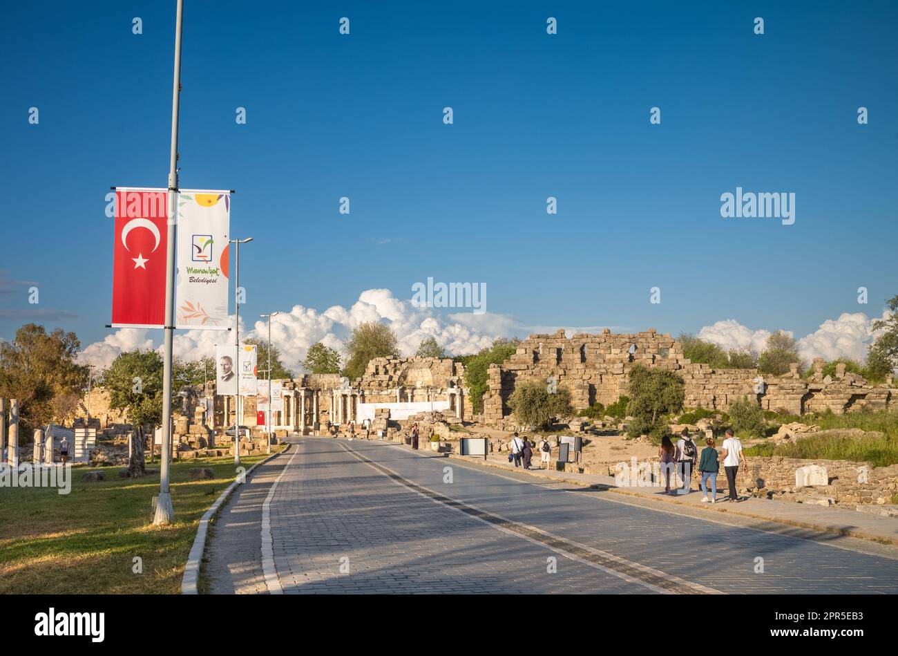 Tourists walk past a Turkish flag and a banner celebrating the founder ...