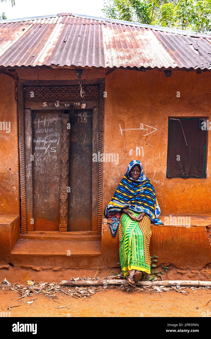 Portrait of beautiful woman relaxing out of traditional African house ...