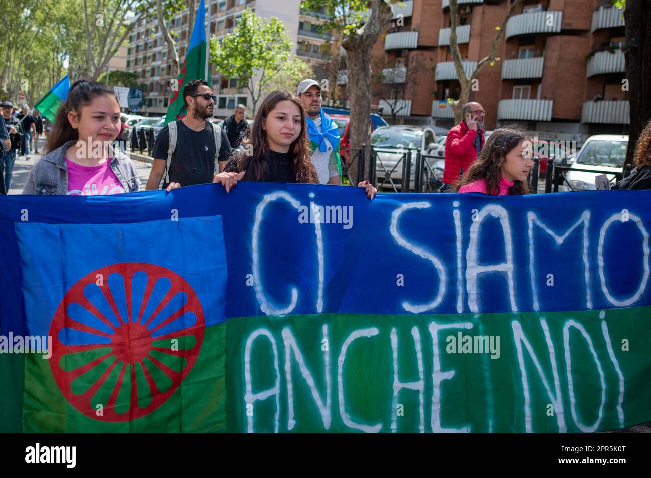Protesters hold a banner bearing the symbol of the Roma Nation ...