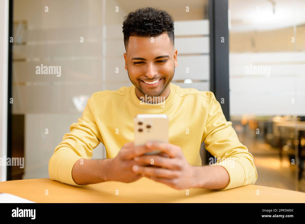 Cheerful young Indian guy spends leisure scrolling news feed on the ...