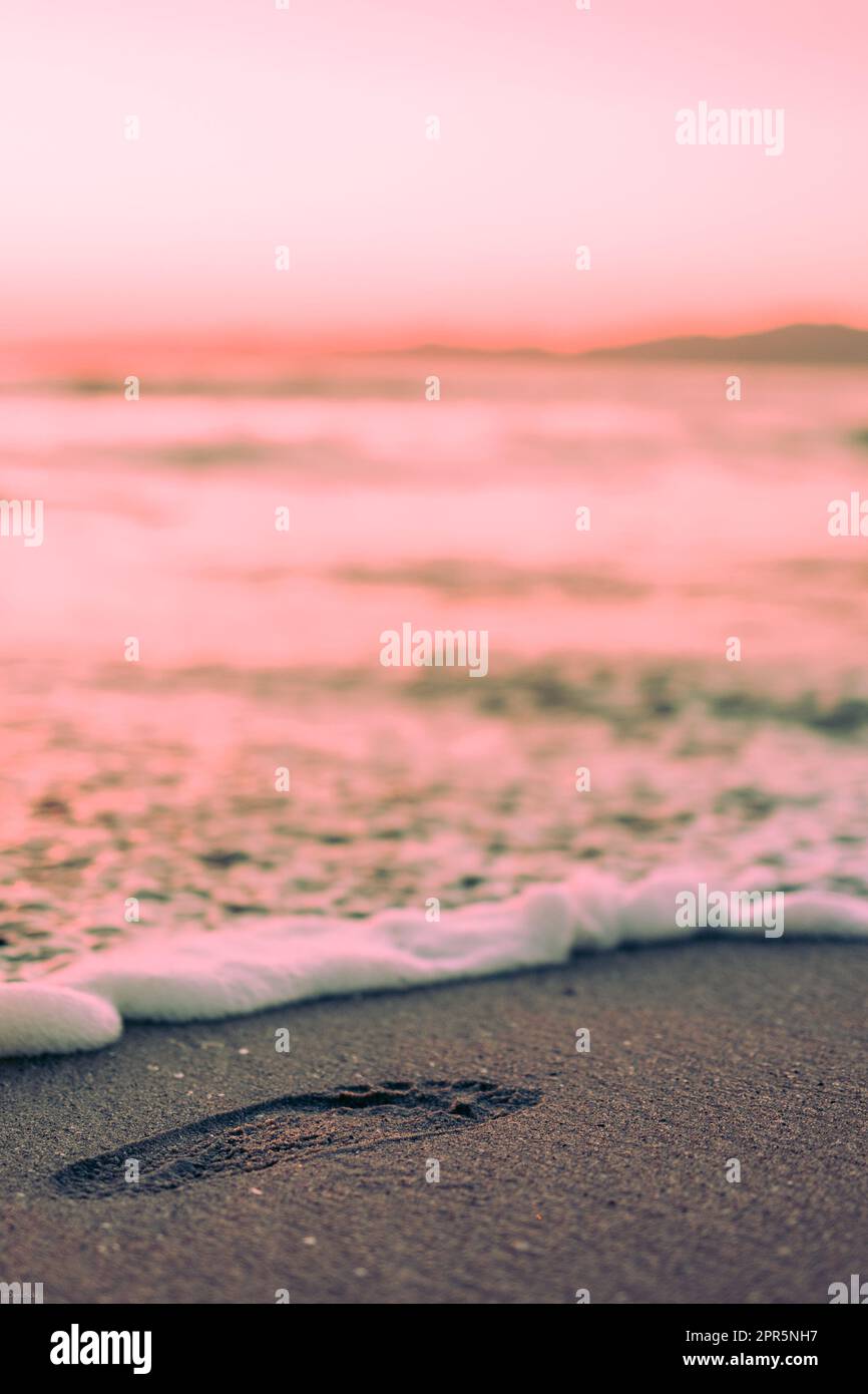 A vertical shot of a footprint in the sand of a beach at sunset Stock ...