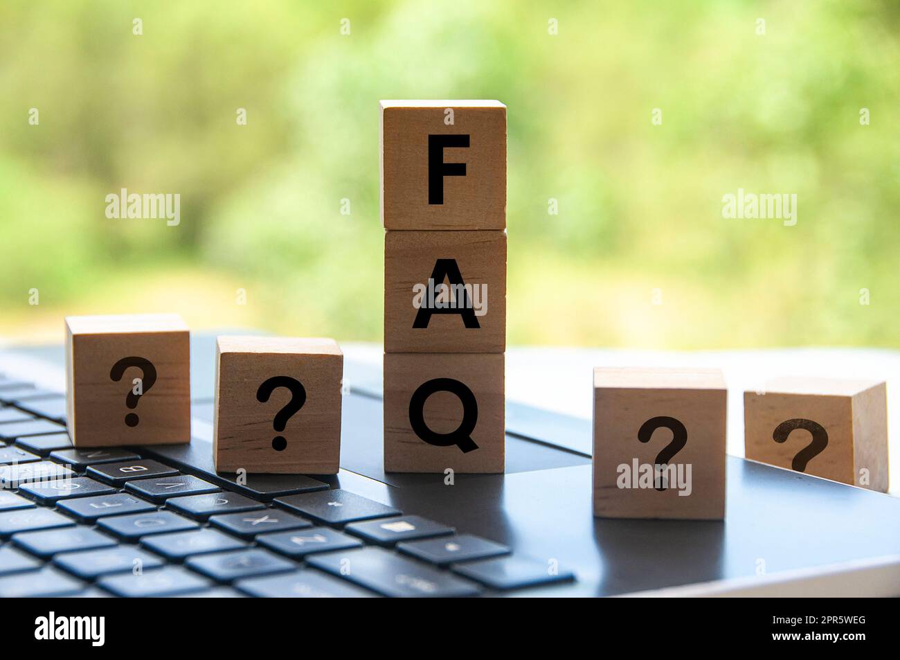 FAQ word on wooden block on top of laptop with blurred nature ...