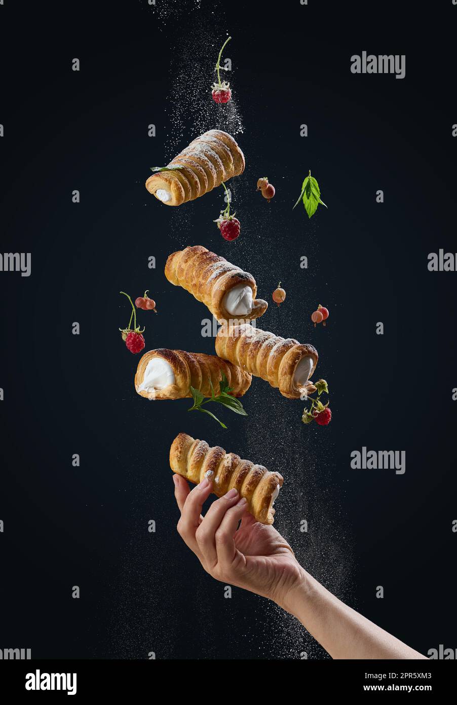 Baked crispy tubes with whipped protein cream levitate on a black ...