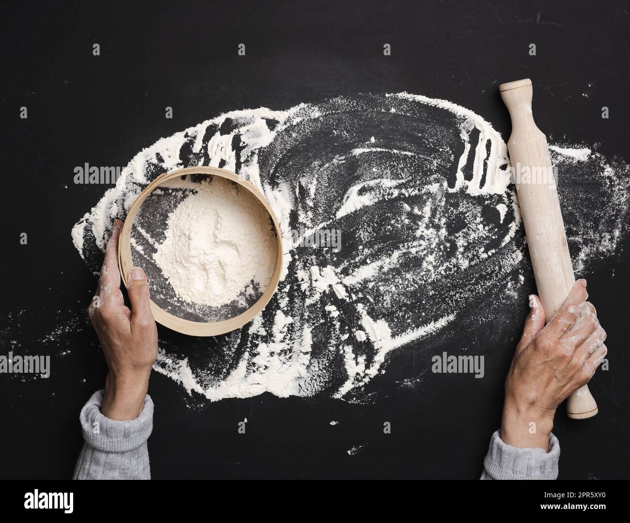 Female hands hold a round wooden sieve with white wheat flour on a ...