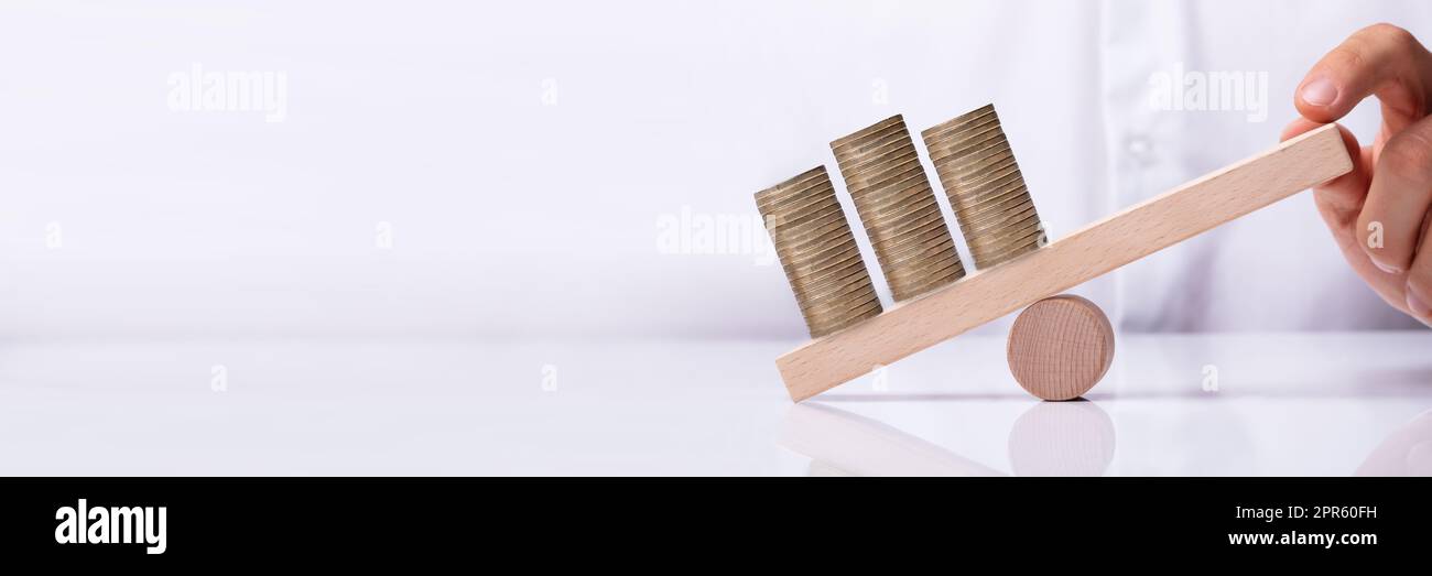 Human Hand Balancing Stacked Coins On Seesaw Stock Photo - Alamy