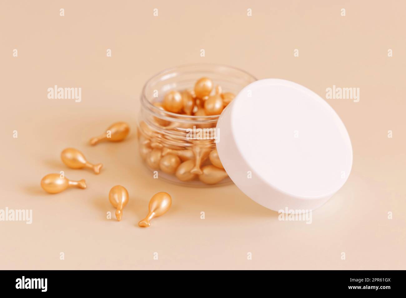 Face serum capsules in an opened jar on light yellow close up. Beauty ...