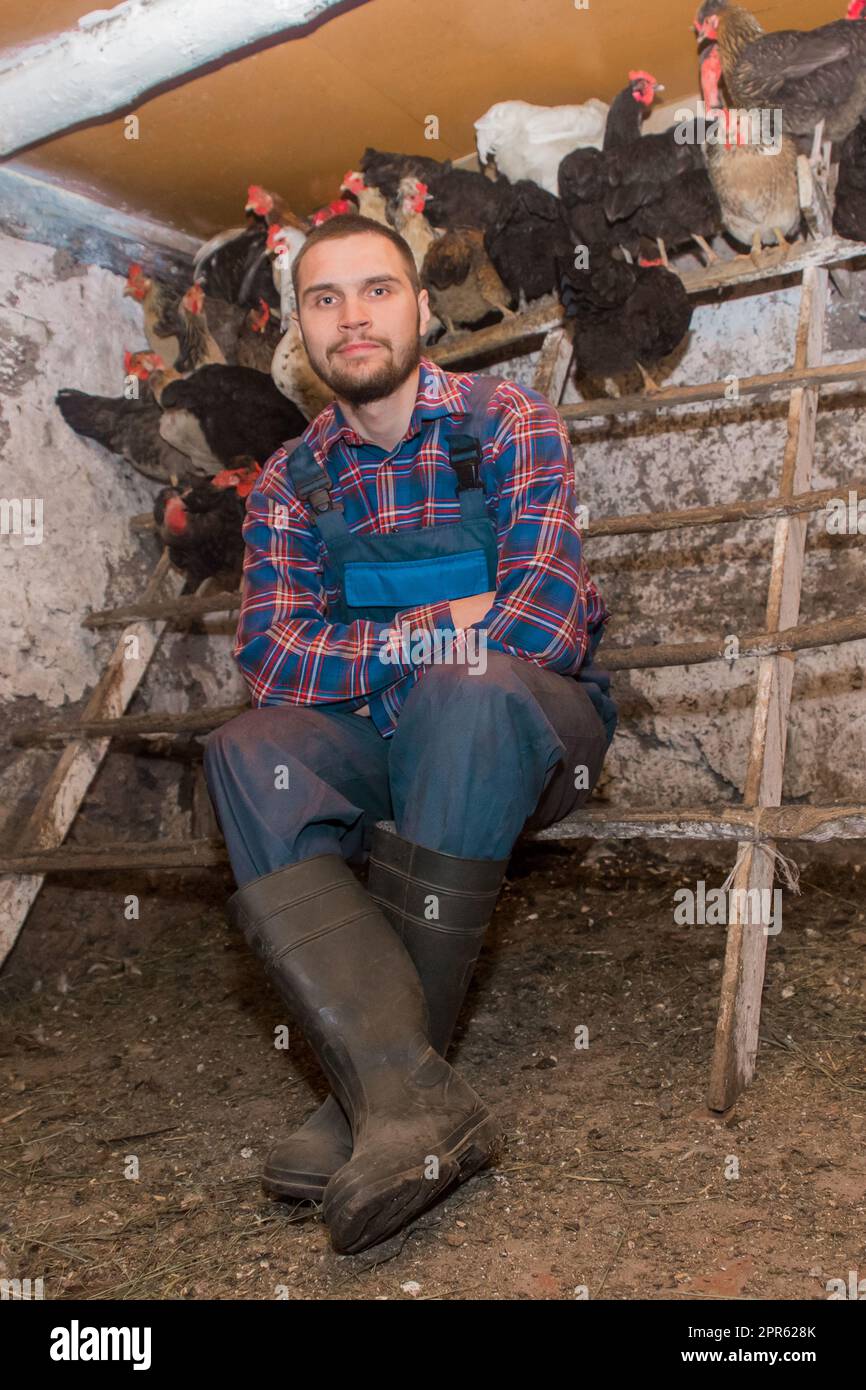A contented farmer of Caucasian appearance, young, handsome, with a beard in a shirt and ...