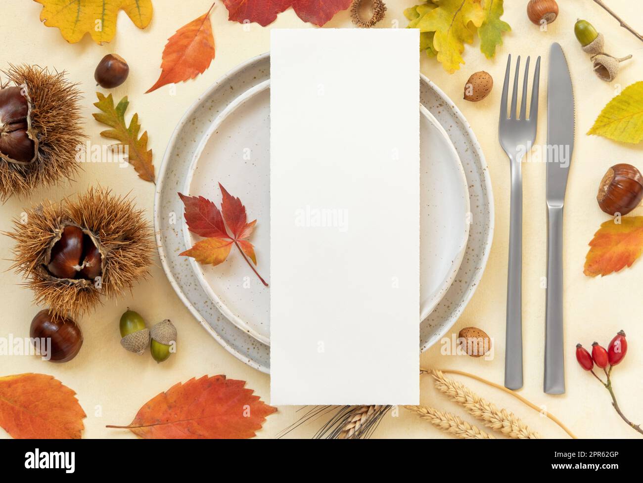 Autumn table place with colorful leaves and vertical blank card top ...