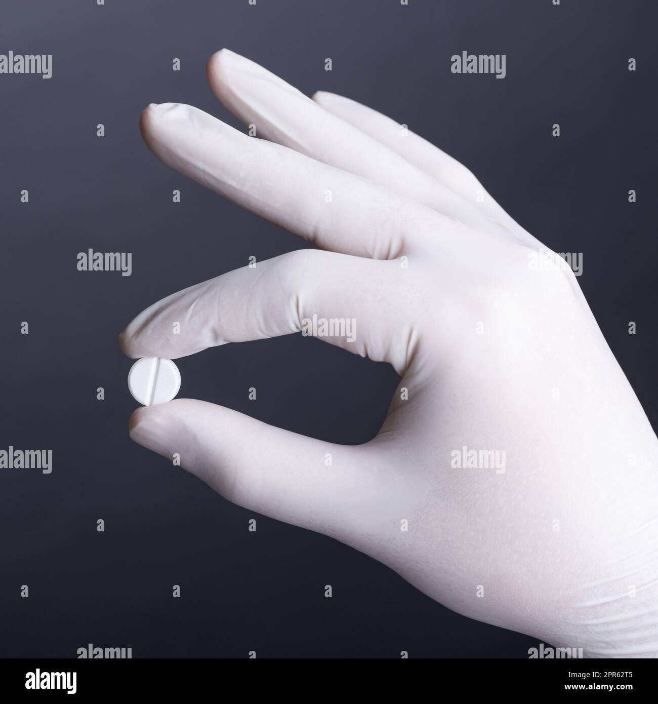 Gloved hand holding a pill Stock Photo - Alamy