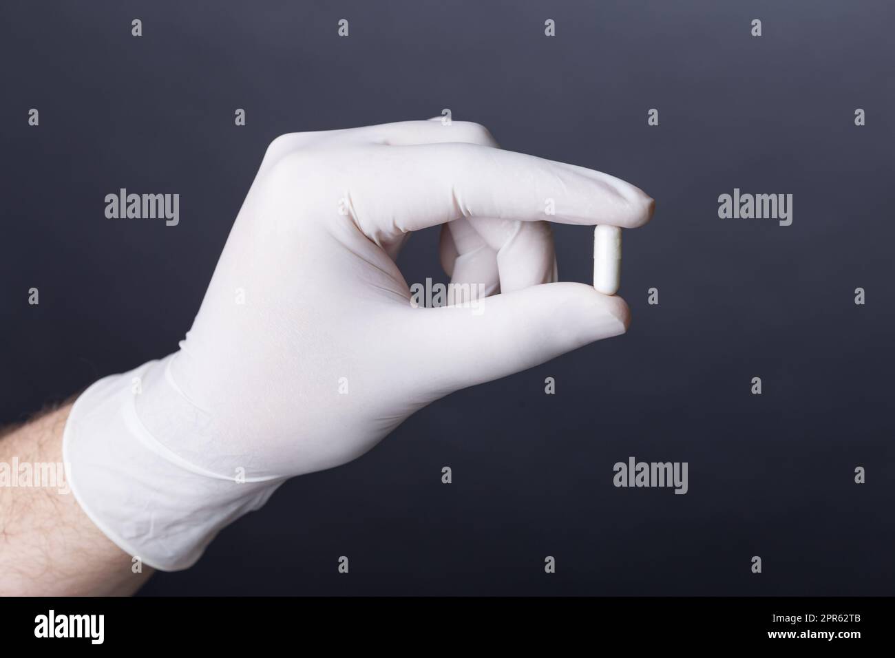 Gloved hand holding a capsule Stock Photo - Alamy