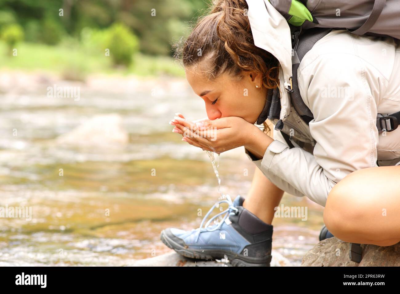 Trekker drinking water directly from river in the mountain Stock Photo ...