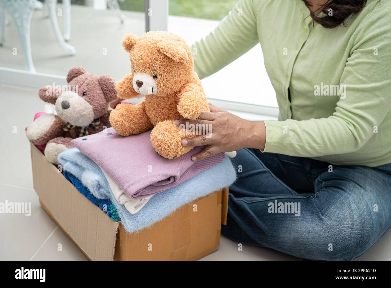 Holding clothing donation box with used clothes and doll at home to ...