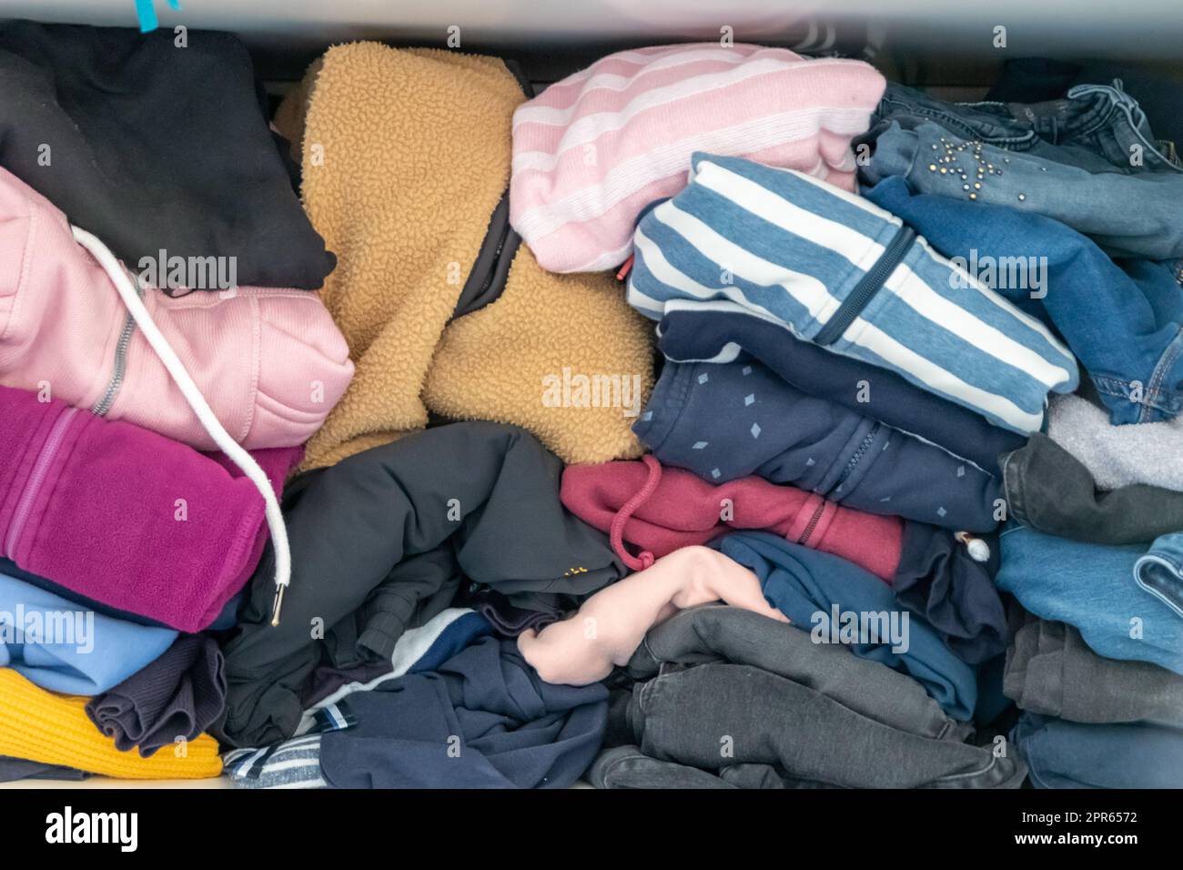 Chaotic wardrobe and sloppy closet shows many outfits of a woman with ...